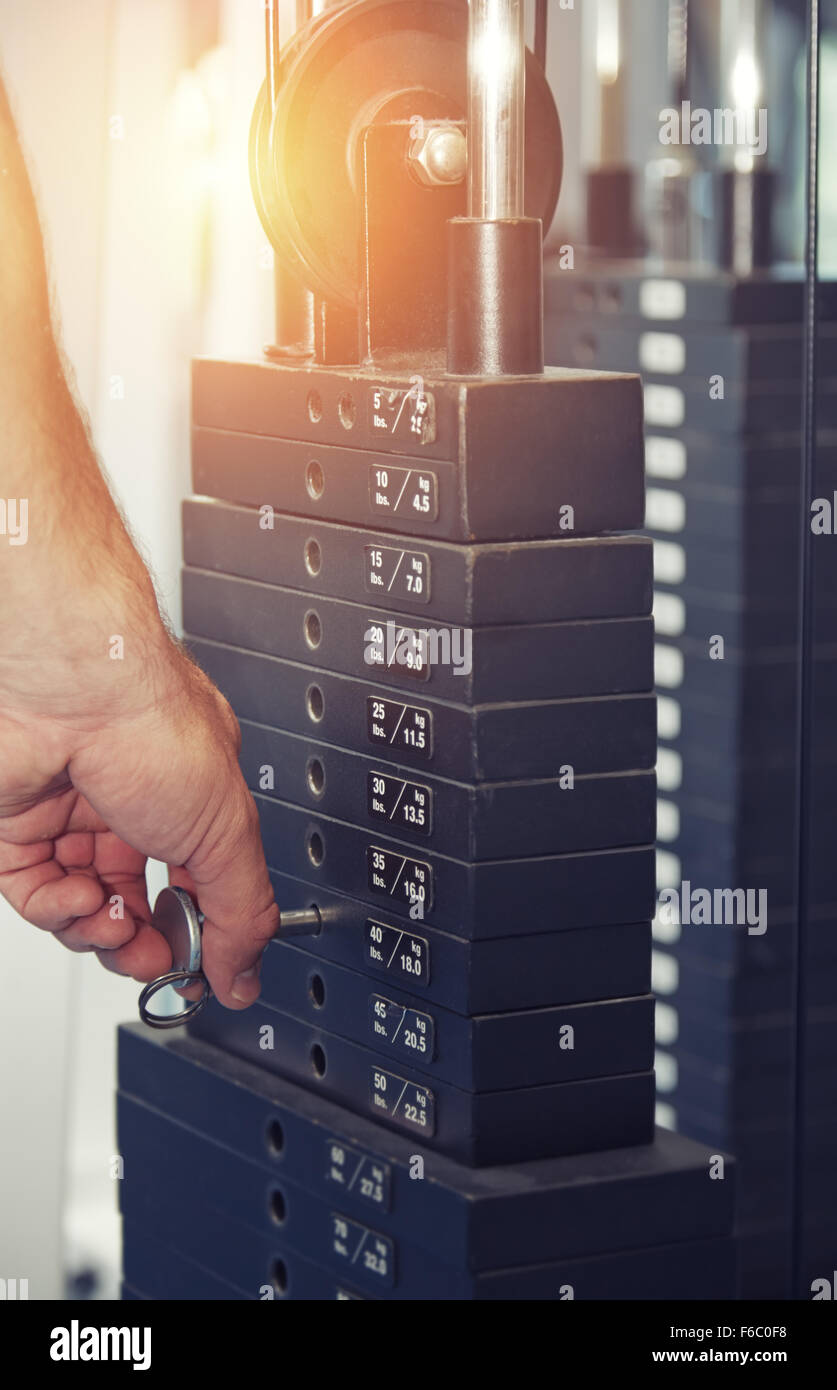 Hand of man adjusting the weight in exercise machine Stock Photo - Alamy