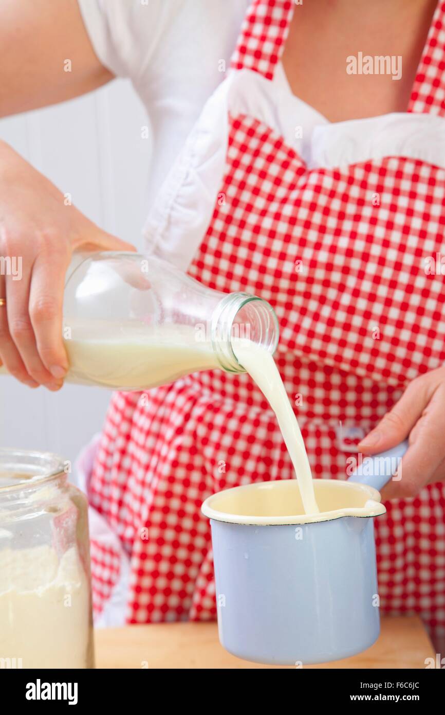A woman pouring milk into a pan Stock Photo - Alamy