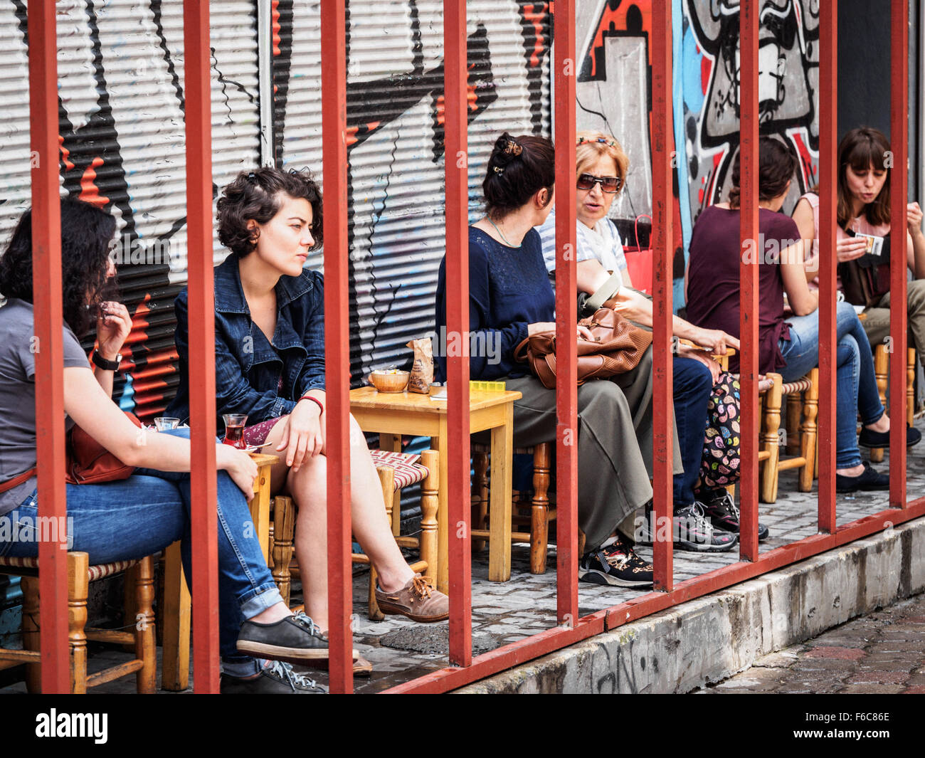 Patrons sitting at small tables in a funky narrow sidewalk cafe ...