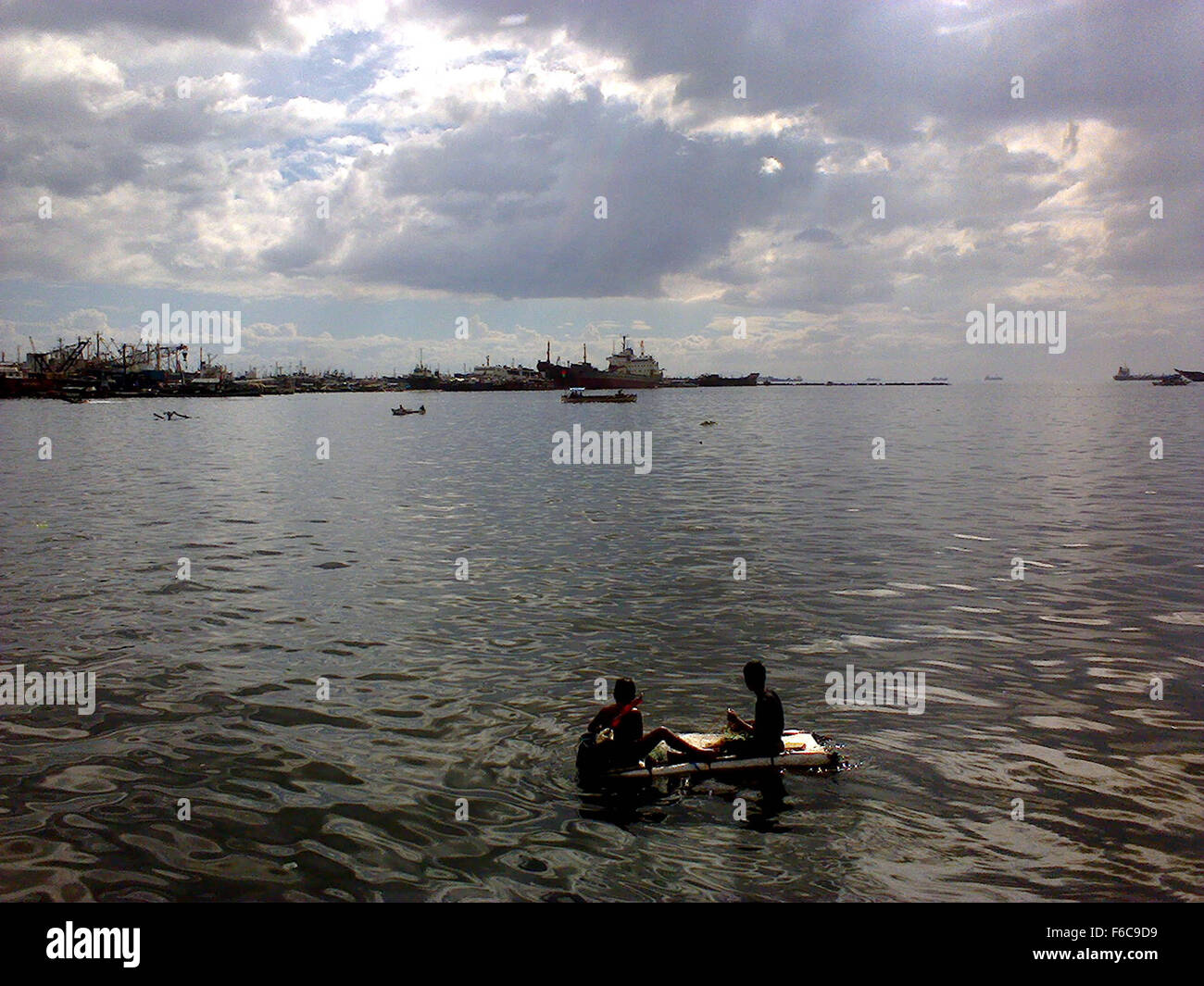 Filipino boys aboard an improvised raft paddle along the coast of ...