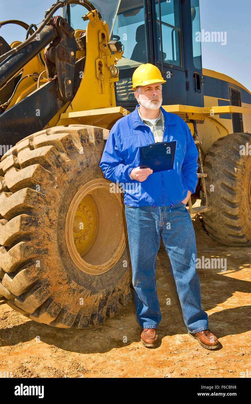 Construction Worker With Clipboard Standing Next to Earthmoving ...