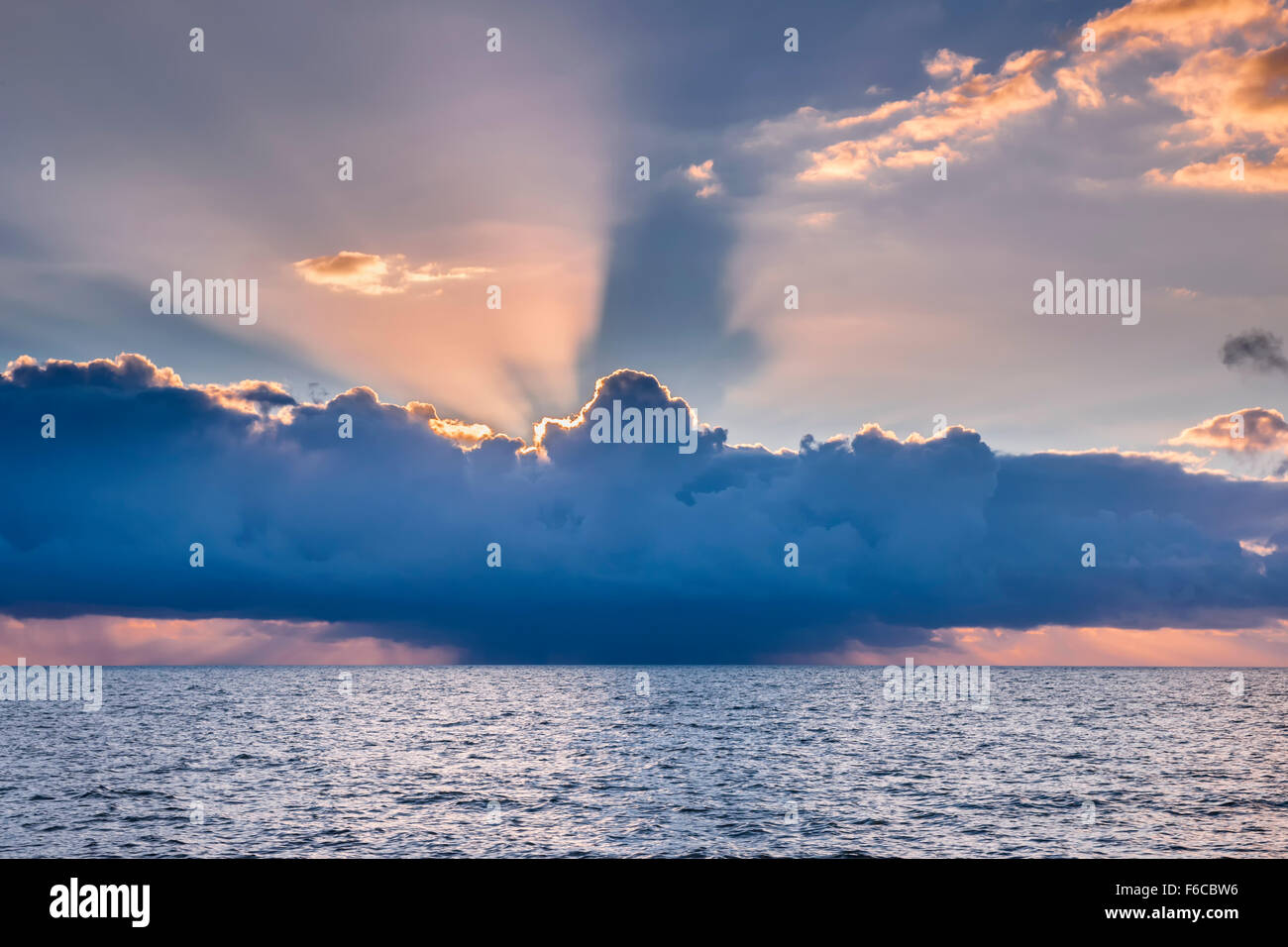 Tropical storm with dark cloud and dramatic sun rays shining through on ...