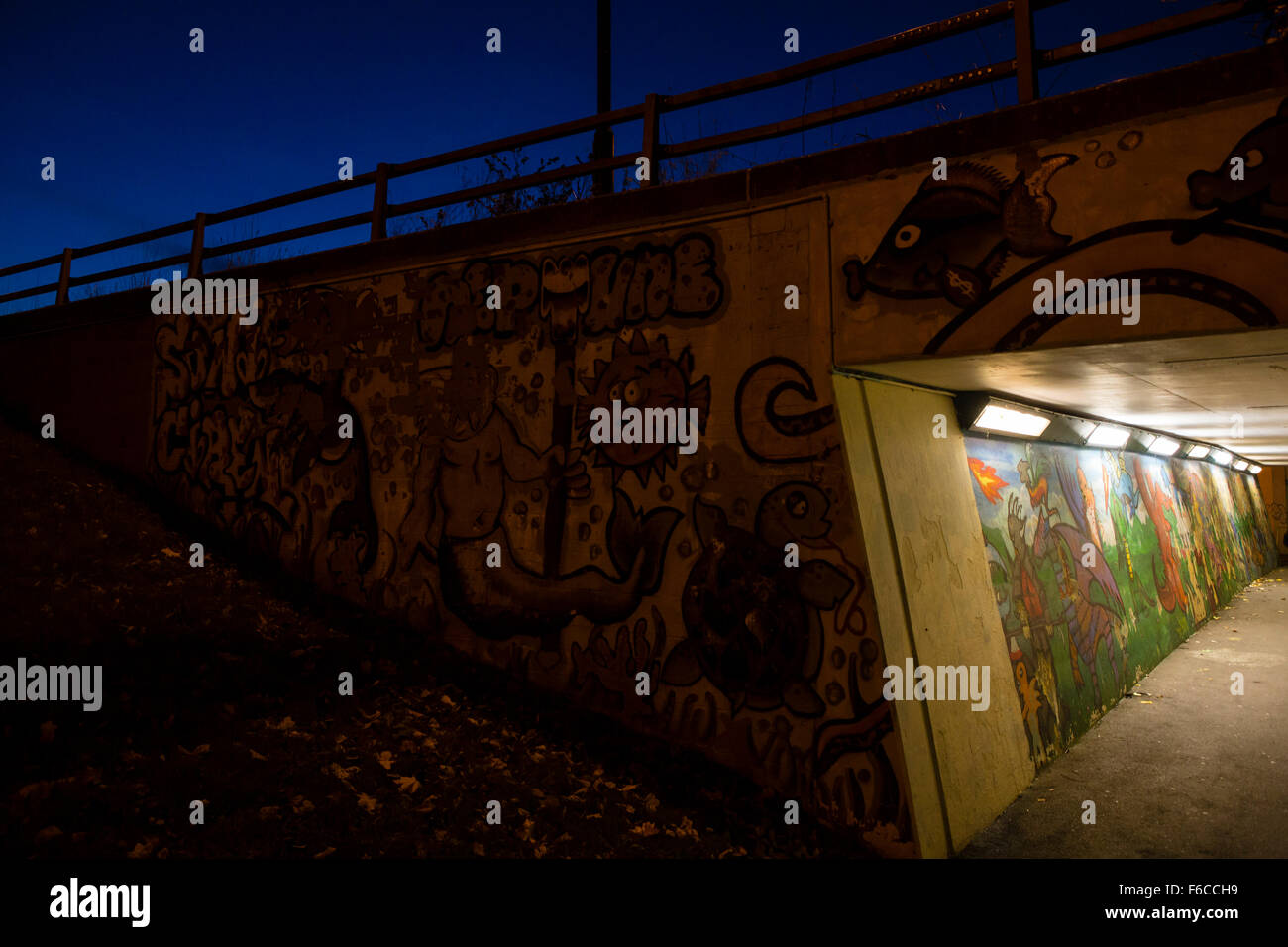 Night time street scene with illuminated underpass and graffiti on a ...