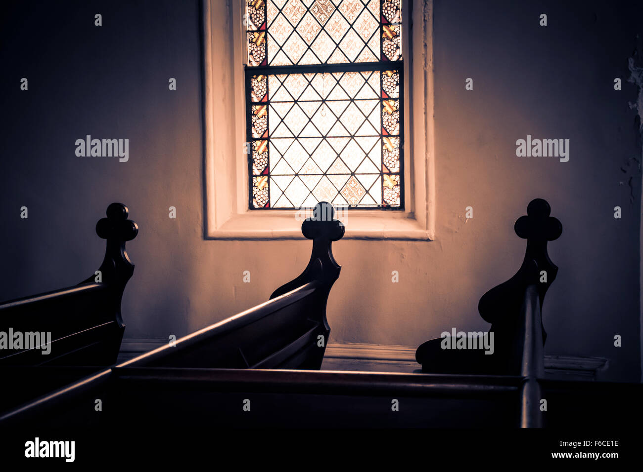 A dimly lit interior from a stained glass church window with carved ...