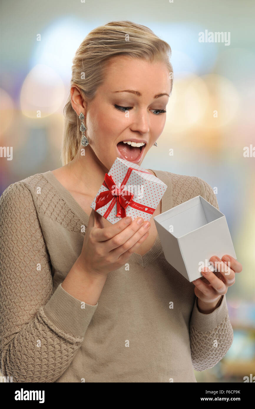 Young woman reacting with surprise when opening gift box Stock Photo ...