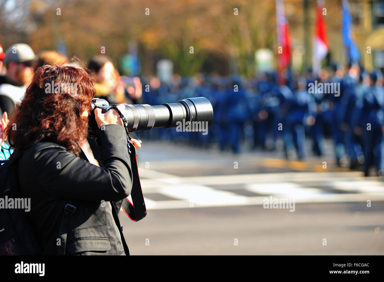 A female photographer holds a very long lens at a remembrance ceremony ...