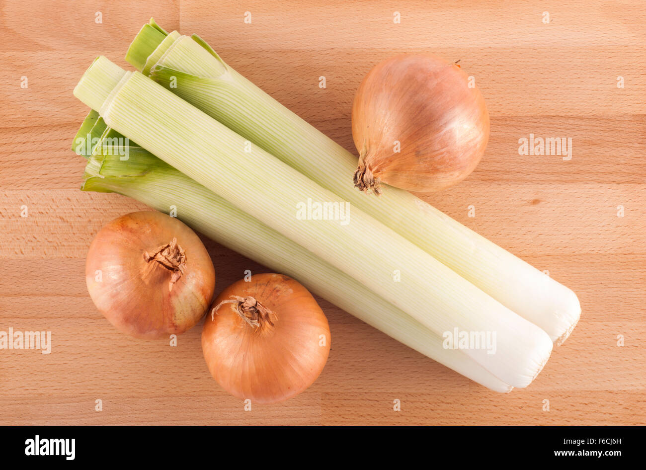 Three fresh Onions and Leeks on a wooden background Stock Photo - Alamy