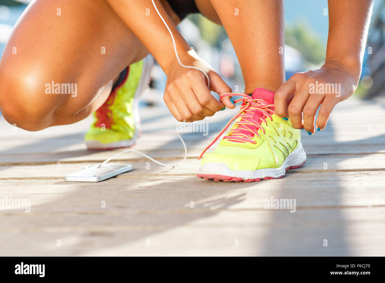 Running shoes - woman tying shoe laces. Closeup of female sport fitness runner getting ready for ...