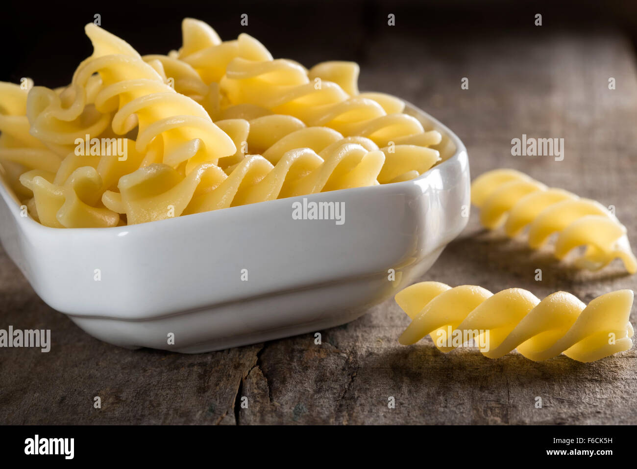 Boiled fusilli pasta in white bowl over wooden background Stock Photo ...