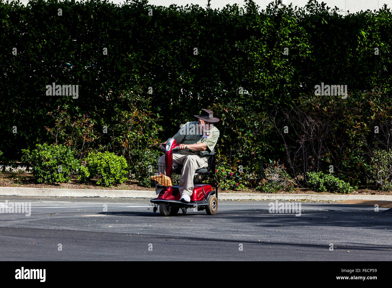 An elderly man riding his Rascal electric scooter leaning into the ...