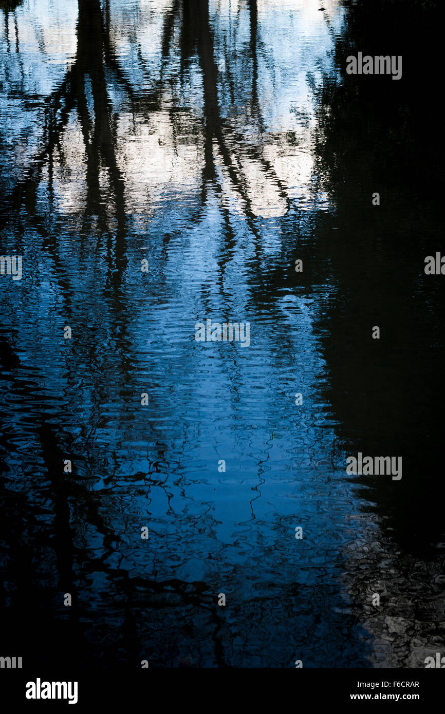 Reflections in a river showing abstract patterns of trees and winter ...