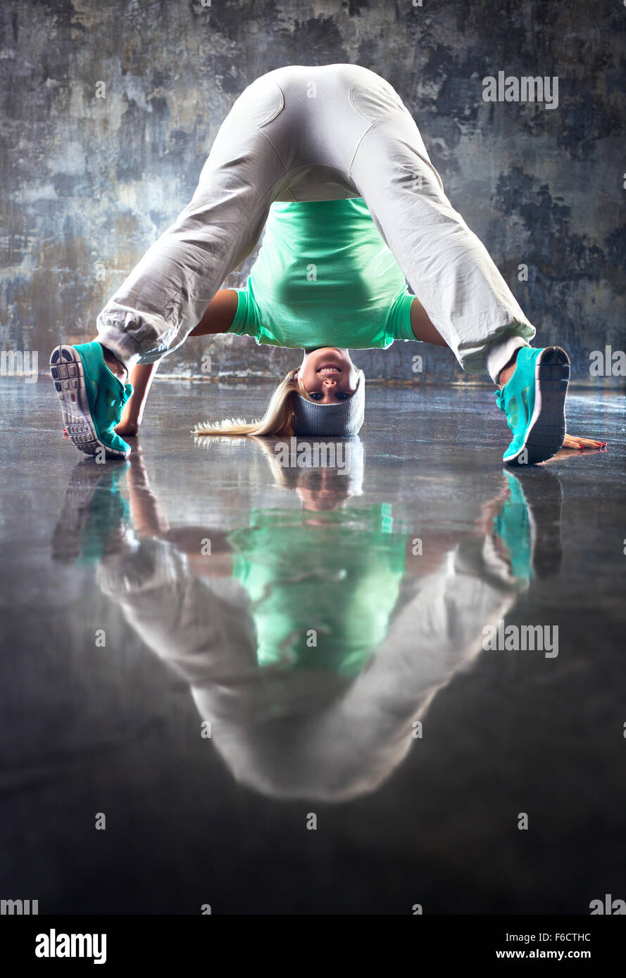 Young smiling woman modern dancer looking on camera upside down. On ...