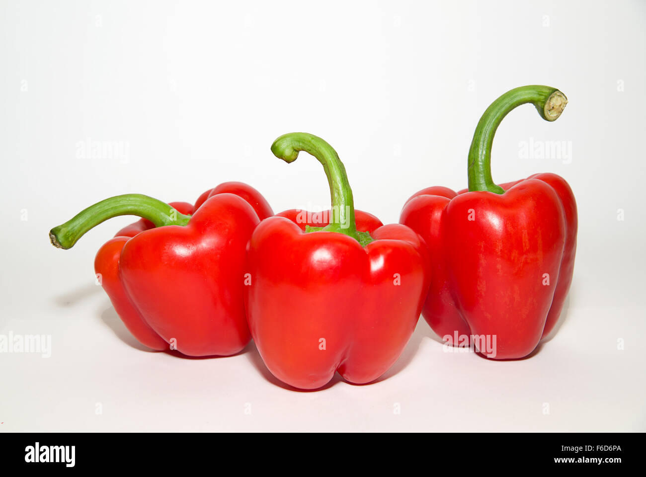 Three red peppers on a white background Stock Photo - Alamy
