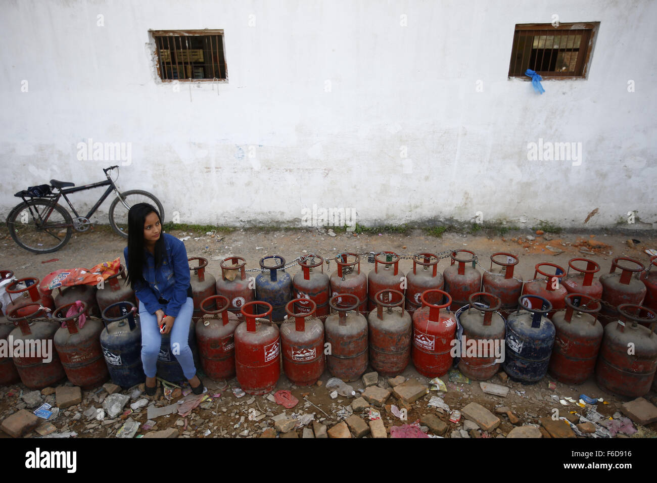 A Nepalese girl sits on top of empty cooking gas cylinders waiting for ...