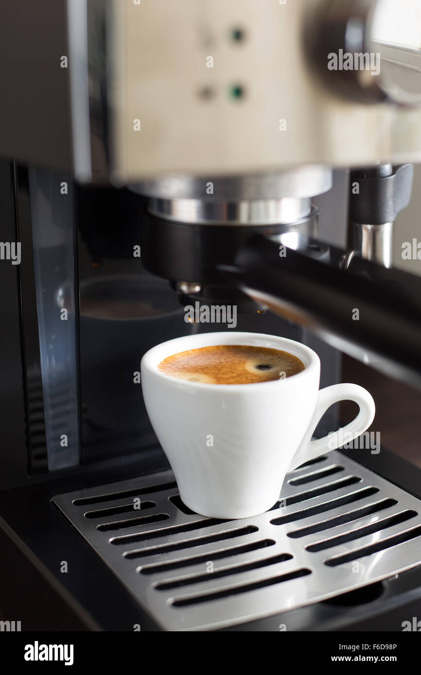 Domestic coffee machine makes cup of espresso. Preparing coffee at home ...