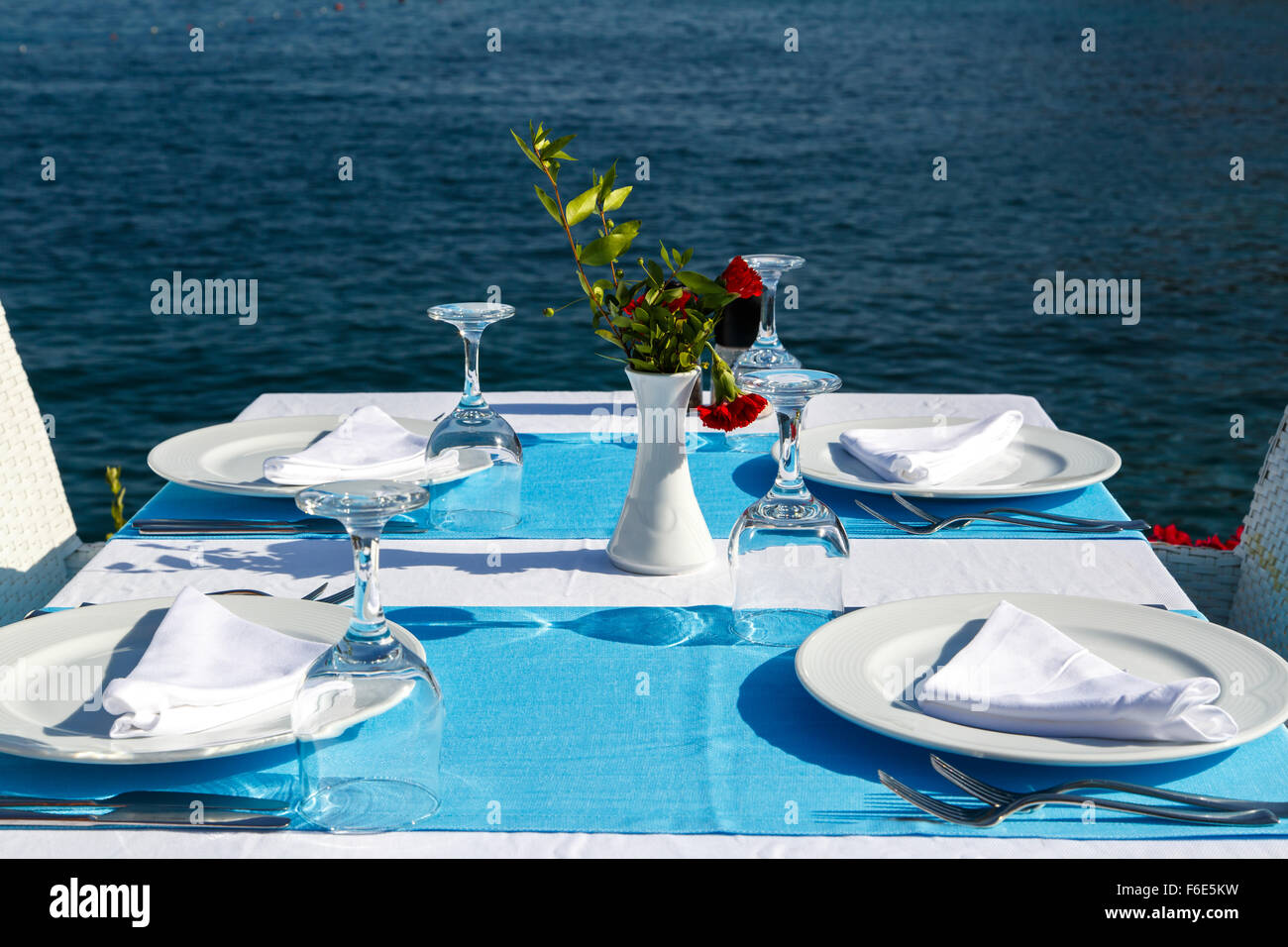 Front view of dinner table with white plates for four on a table with ...