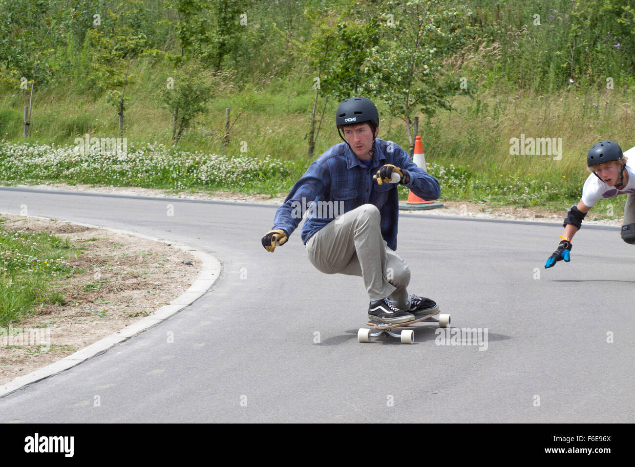 Skateboarders racing downhill lean to take a right hand bend Stock ...