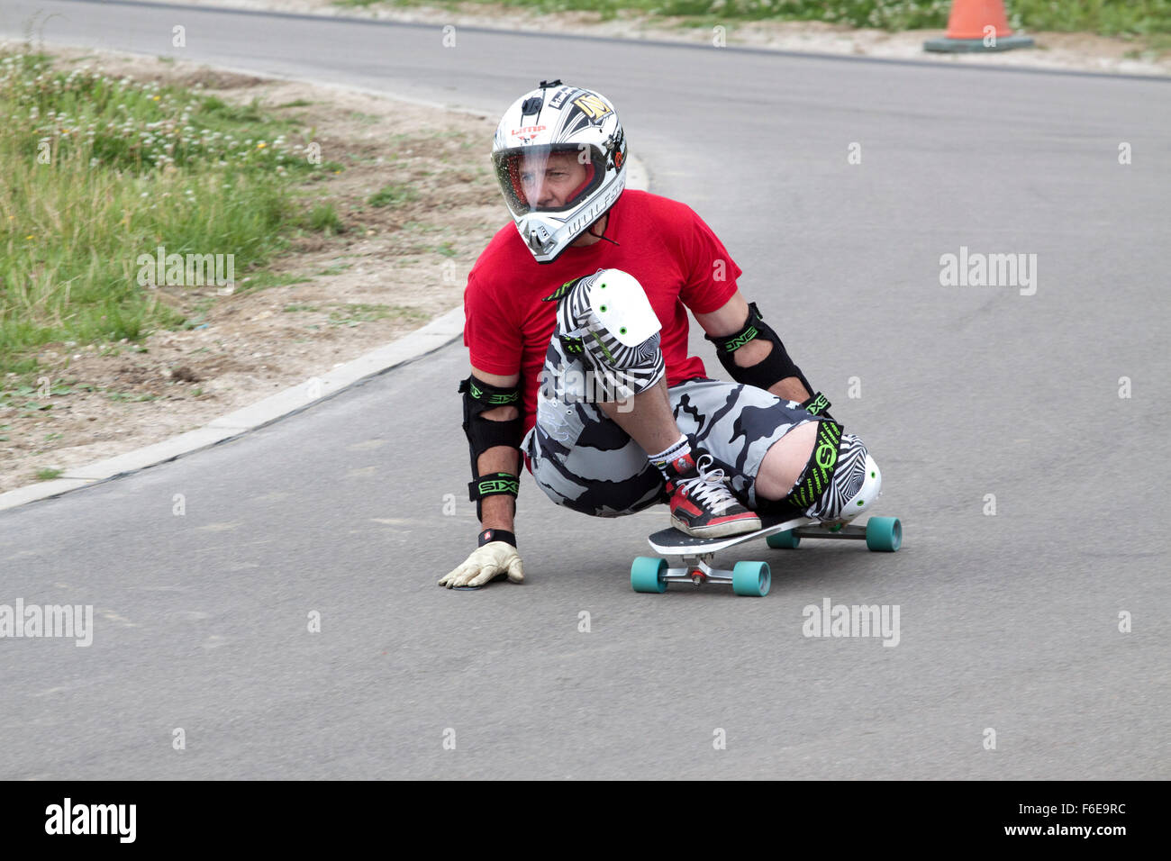 Skateboarders racing downhill lean to take a right hand bend Stock ...