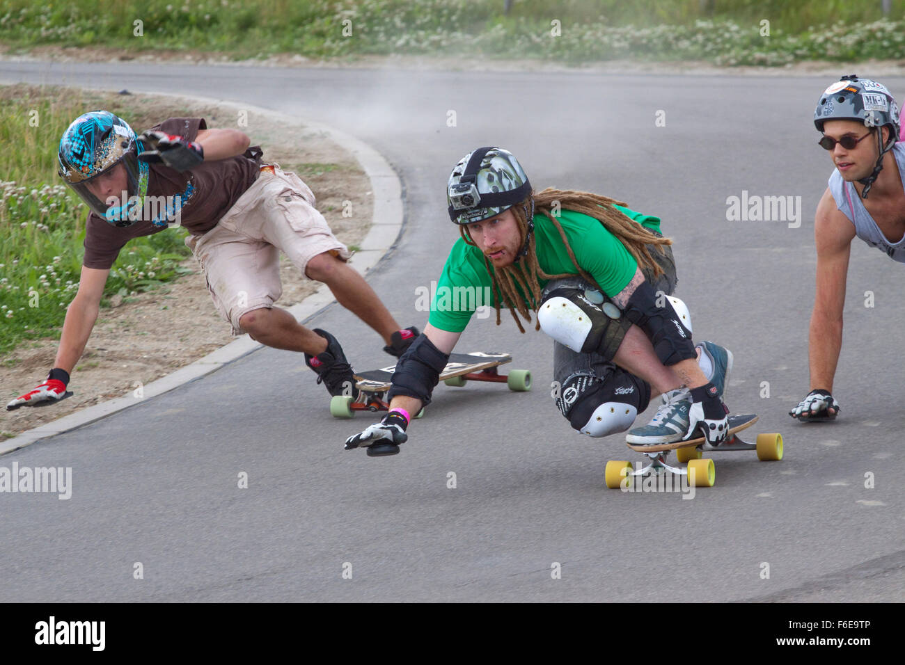 Skateboarders racing downhill lean to take a right hand bend Stock ...