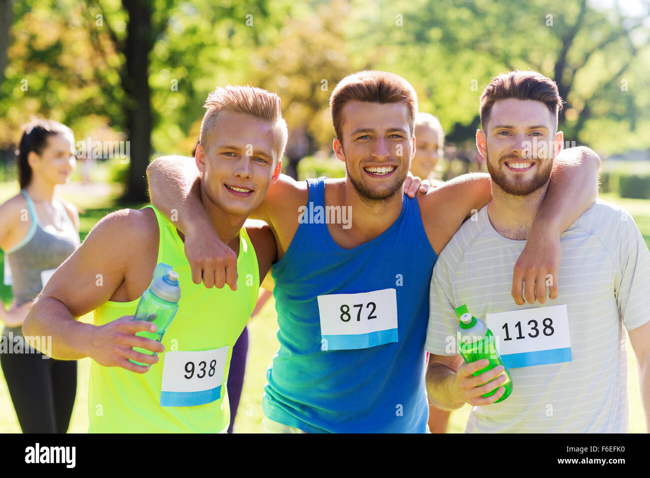 happy friends with racing badge numbers and water Stock Photo - Alamy