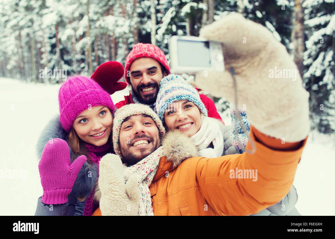 smiling friends with camera in winter forest Stock Photo - Alamy