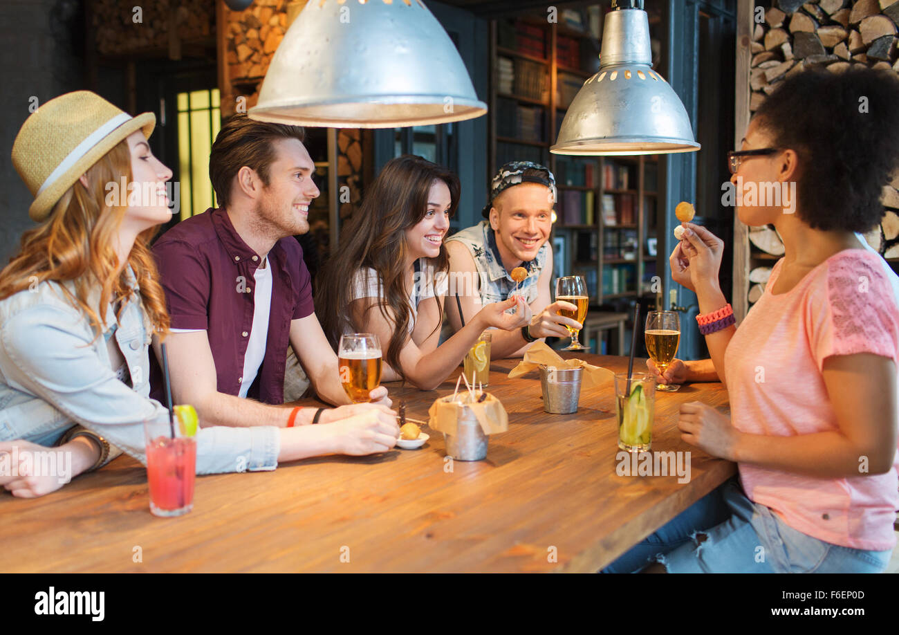 happy friends with drinks talking at bar or pub Stock Photo - Alamy