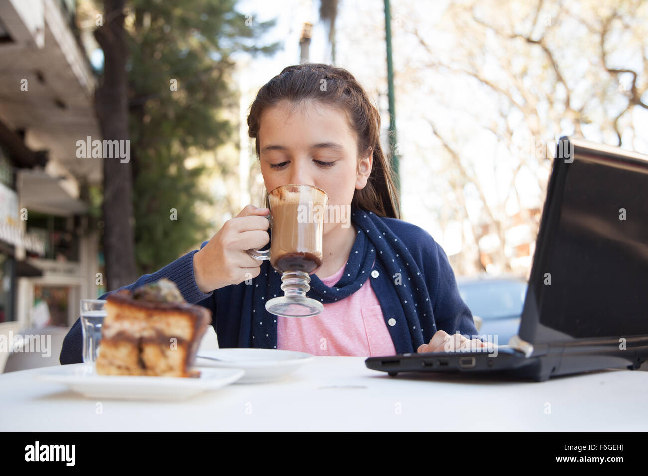 Girl using the computer while she drinks coffee Stock Photo - Alamy