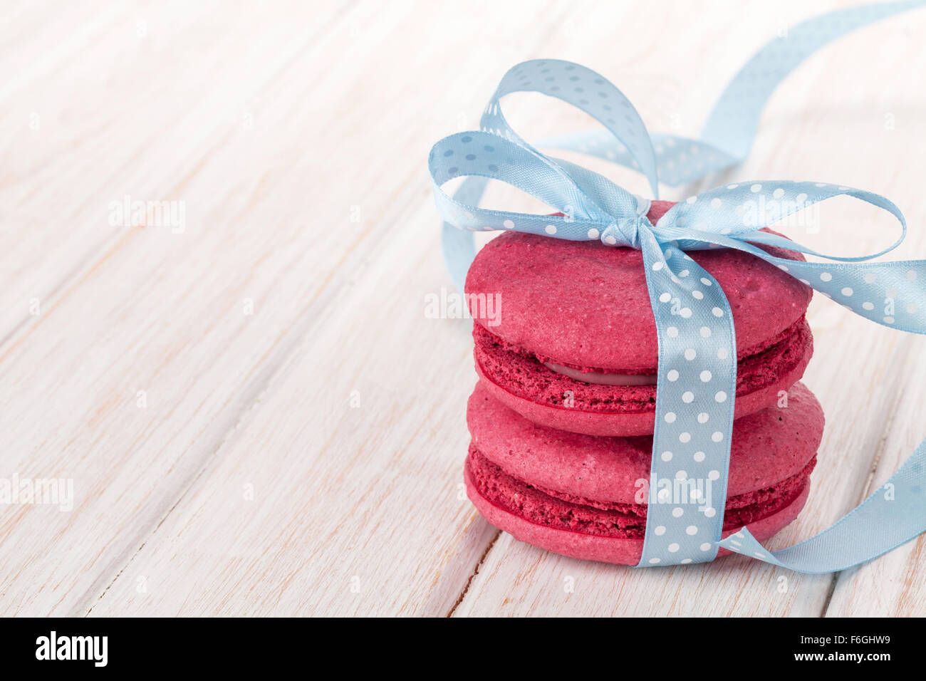 Red macarons with blue ribbon on white wooden table Stock Photo - Alamy