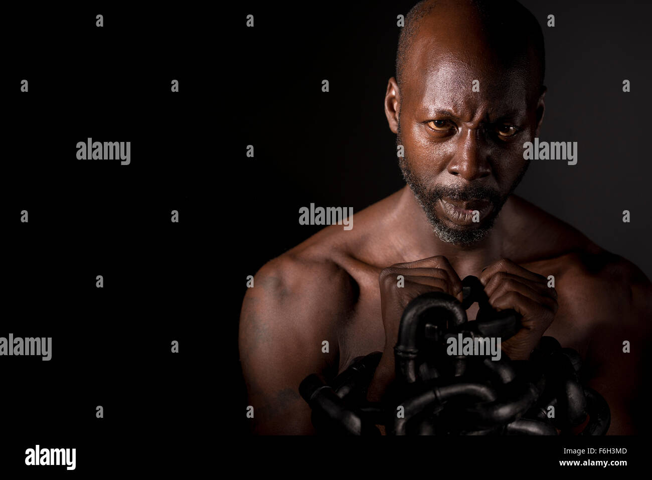 Black man, staring at camera, with his hands and wrists tied by heavy ...