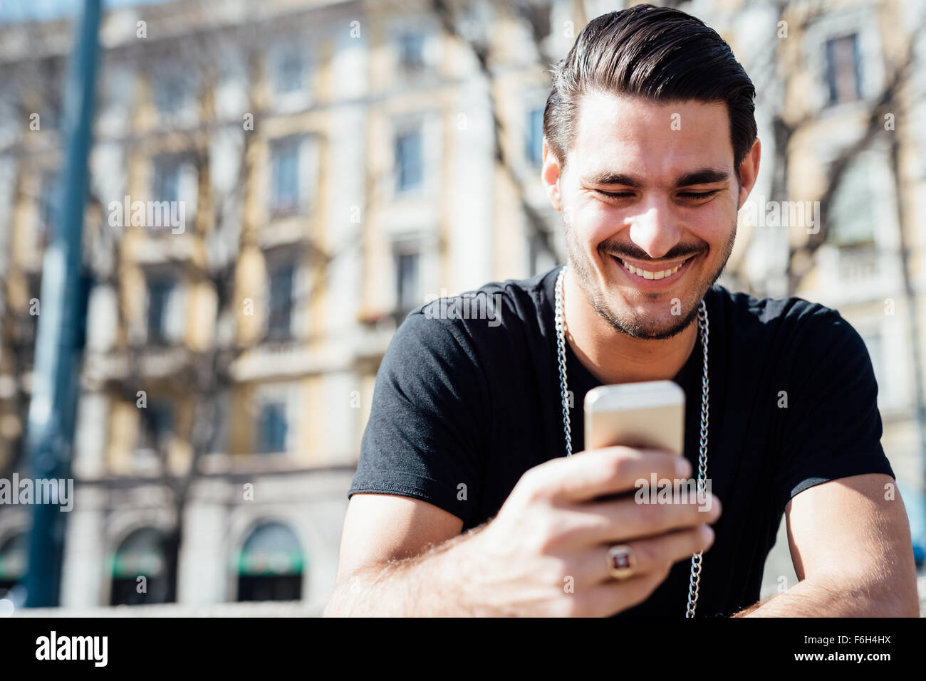 Portrait of a young handsome italian boy using a smartphone connected ...