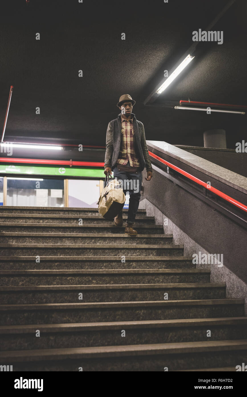 Young handsome afro black man going downstairs in the underground ...