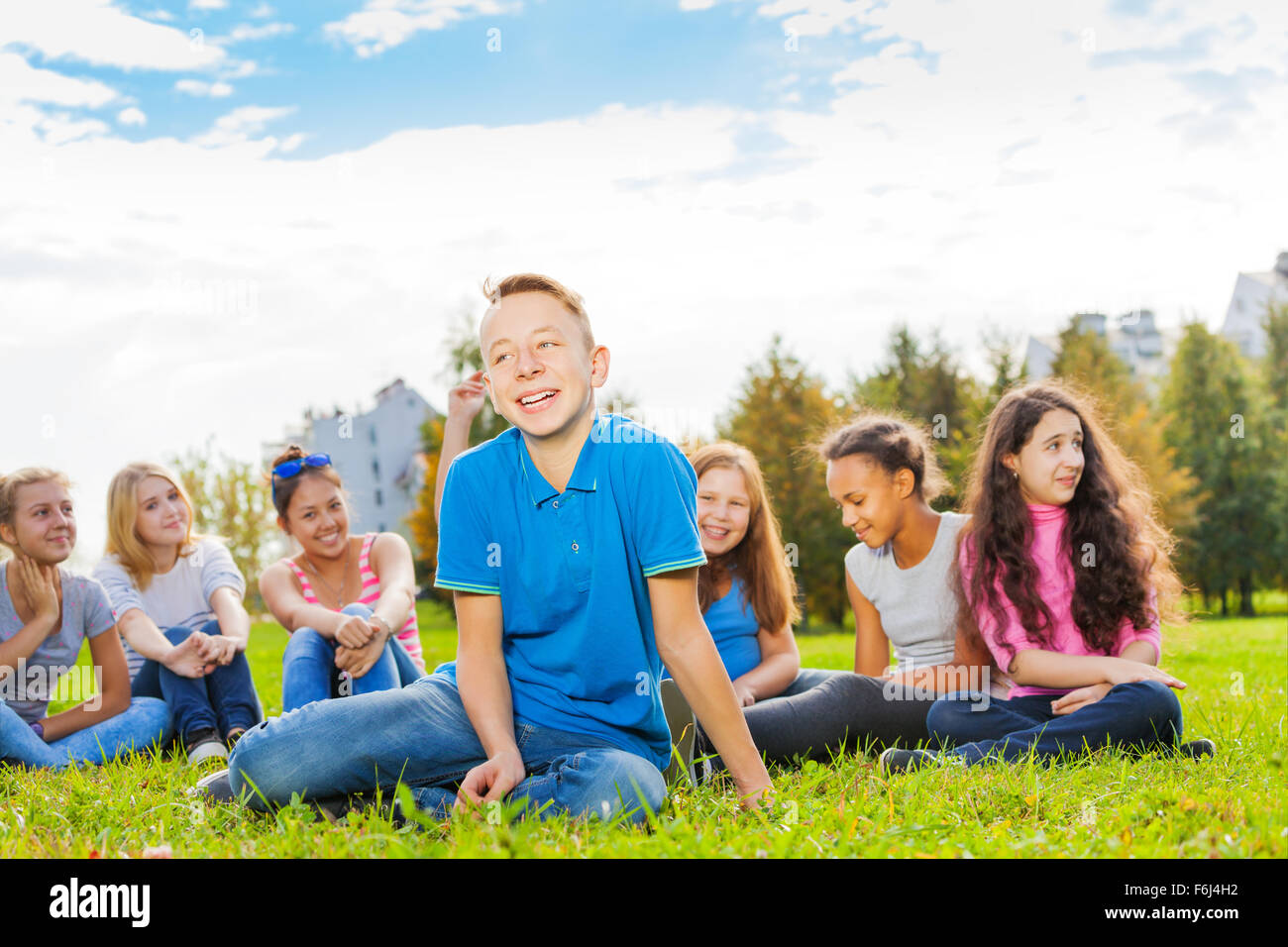 Laughing boy and friends sitting together in park Stock Photo - Alamy