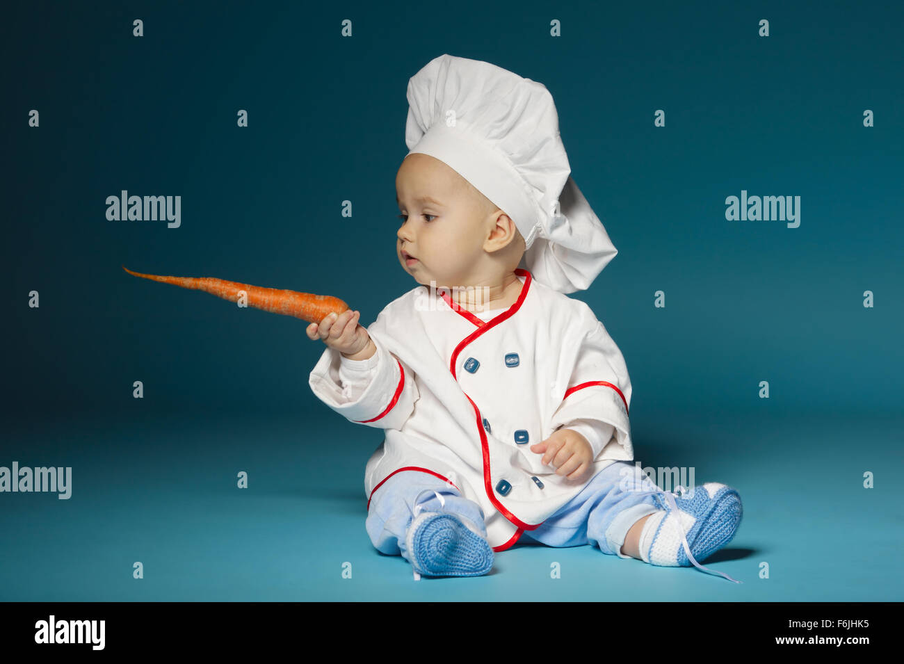 funny baby with cook costume holds carrot Stock Photo - Alamy