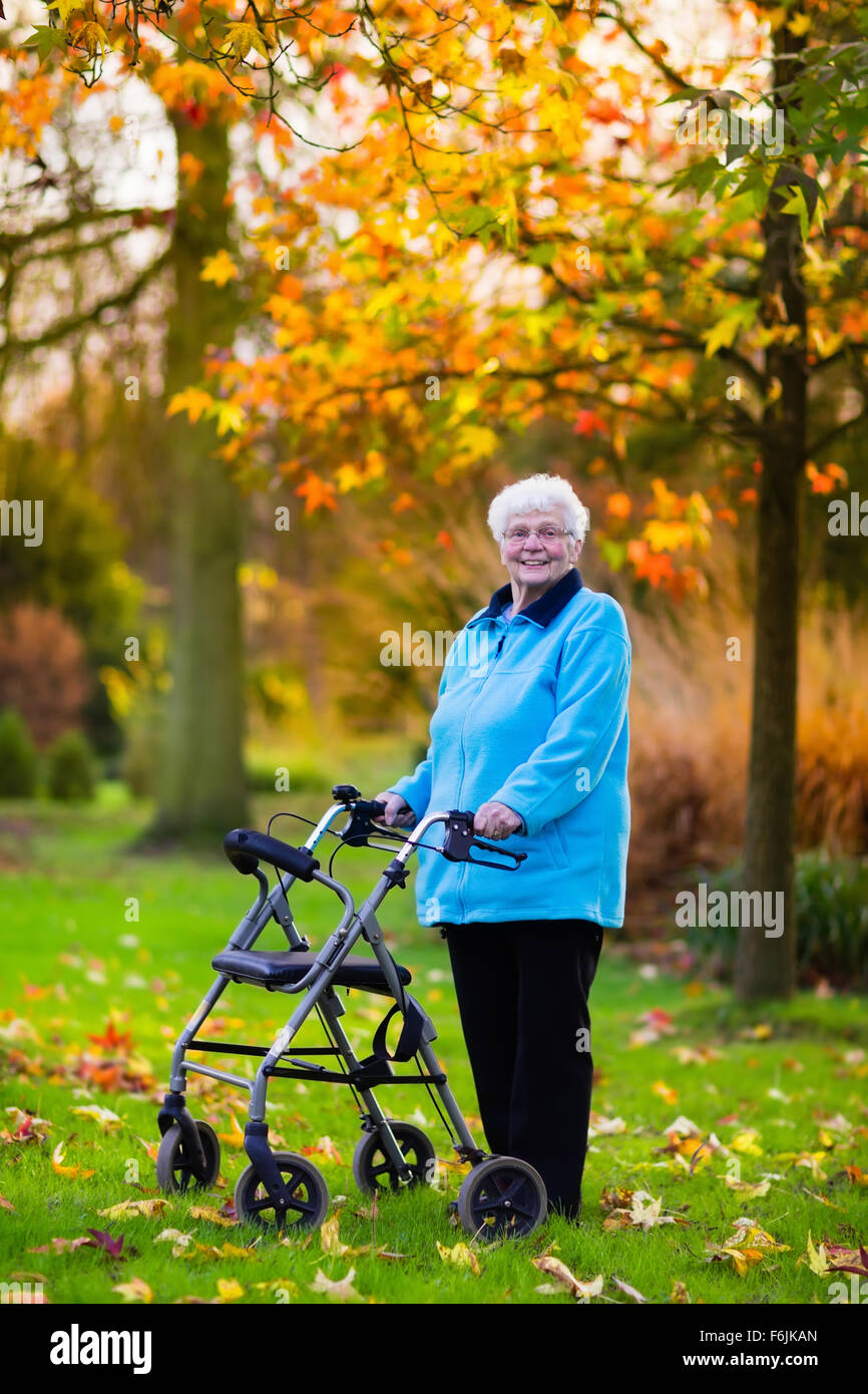 Happy senior handicapped lady with a walking disability enjoying a walk ...