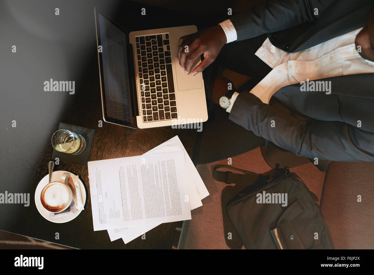 Top view of businessman sitting at coffee shop working on laptop ...