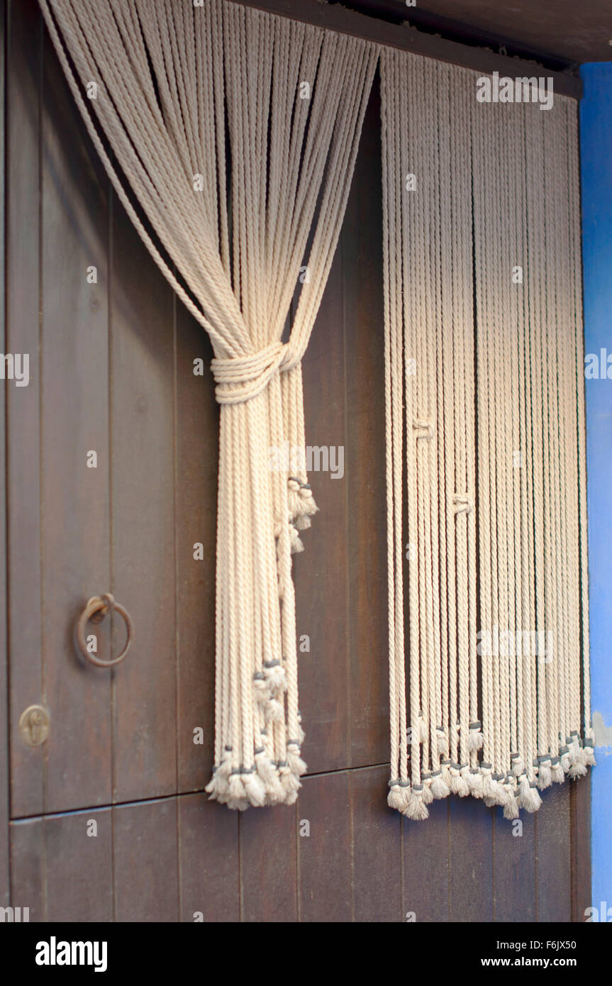 Door in a village divided with a curtain made of ropes to avoid flies ...