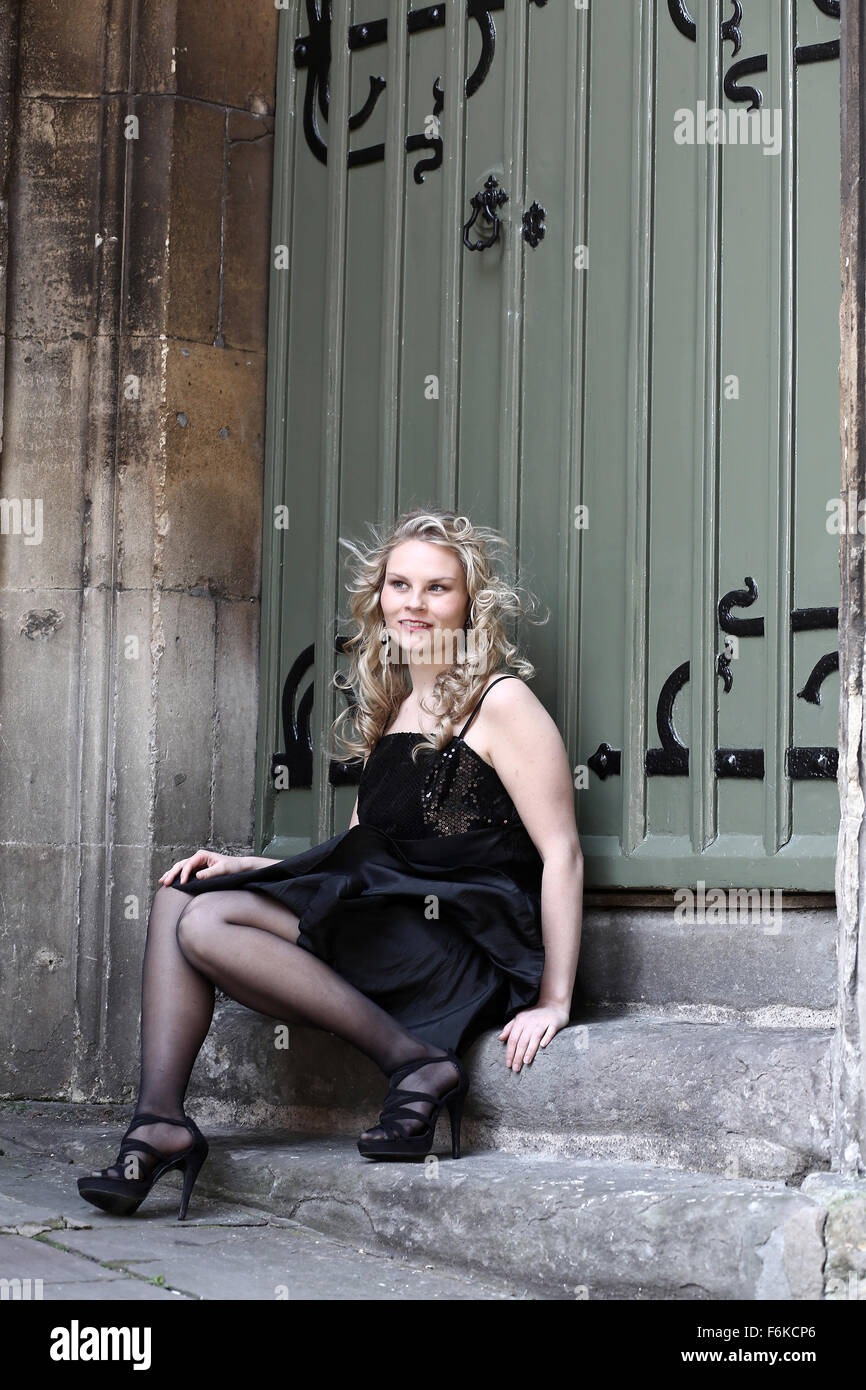Beautiful blonde young woman in a dress on steps in the city of Bristol ...