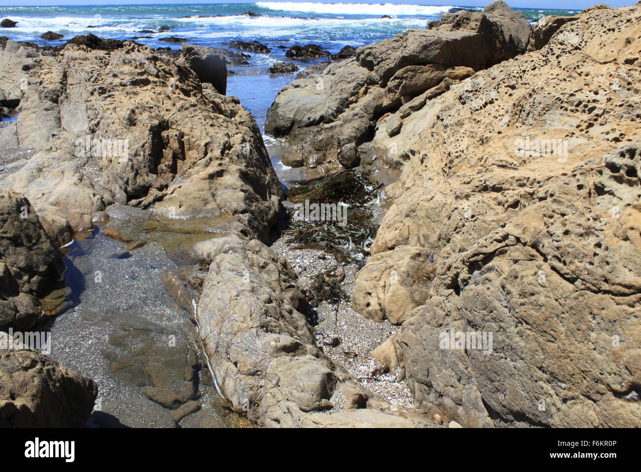 Waves come in thought the rock creating a small pool, some of this are ...