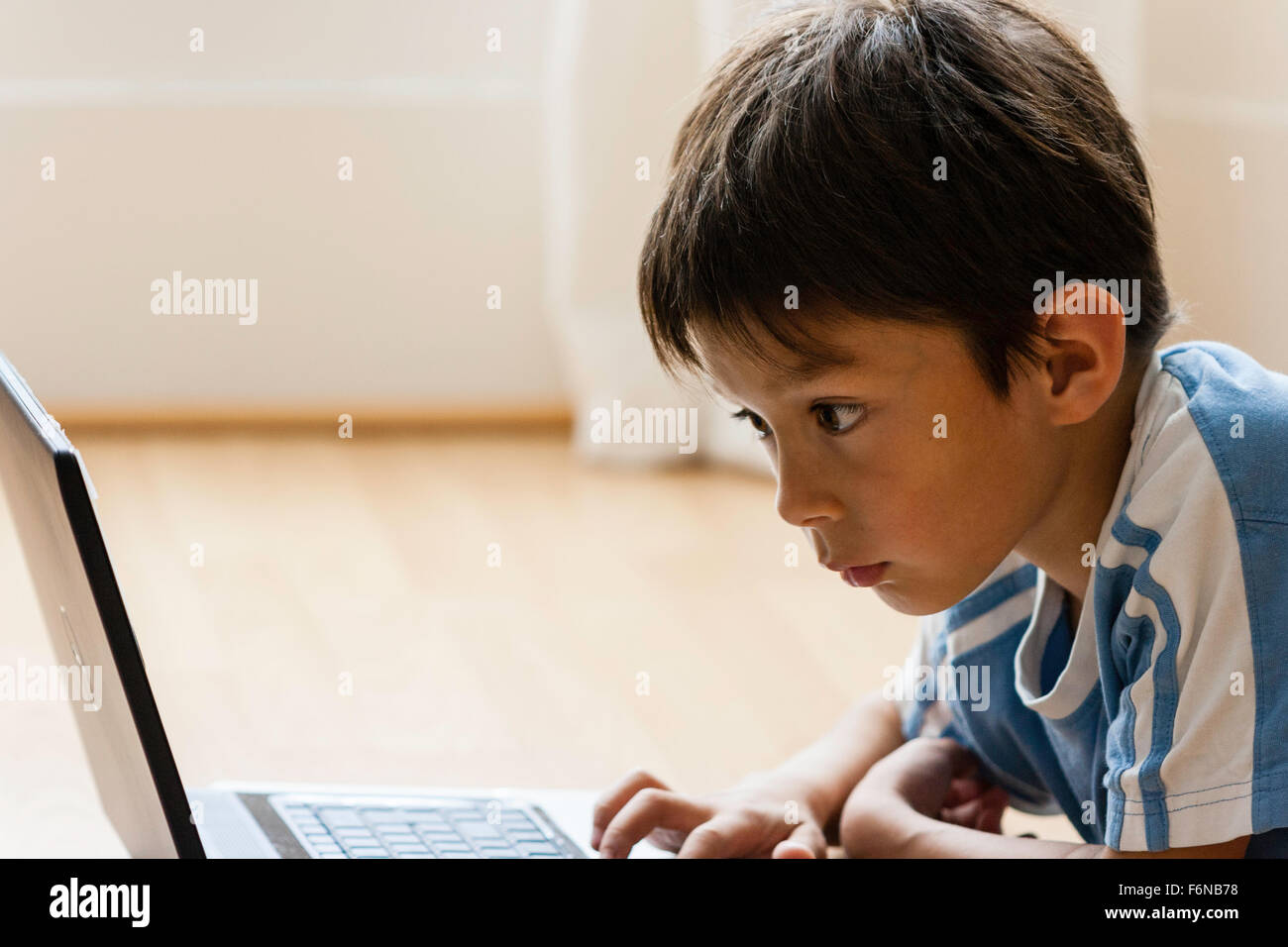 Side view of Caucasian child, boy, 7-8 year old, laying on floor using ...