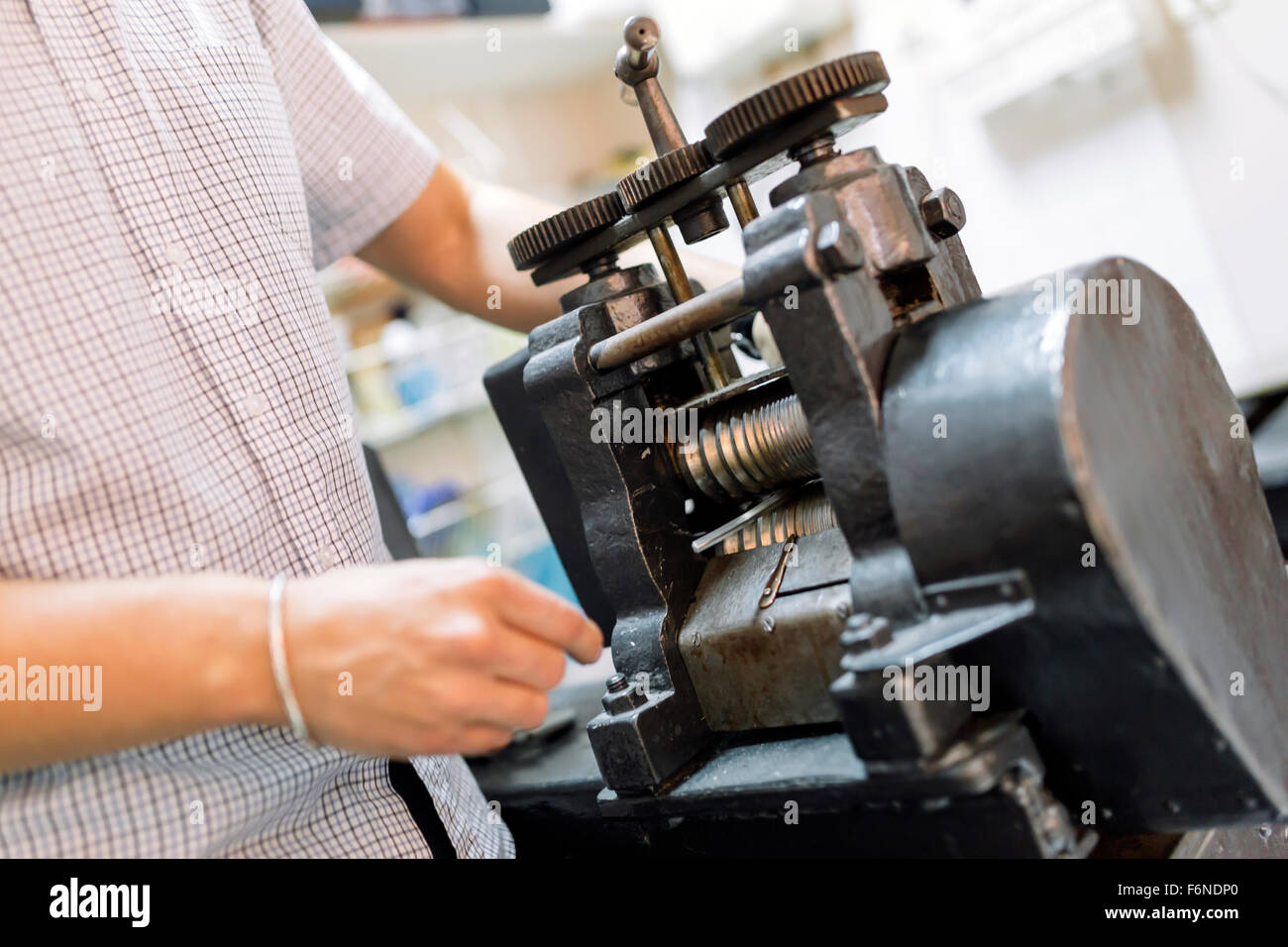 Goldsmith using machine to make metal thinner Stock Photo - Alamy