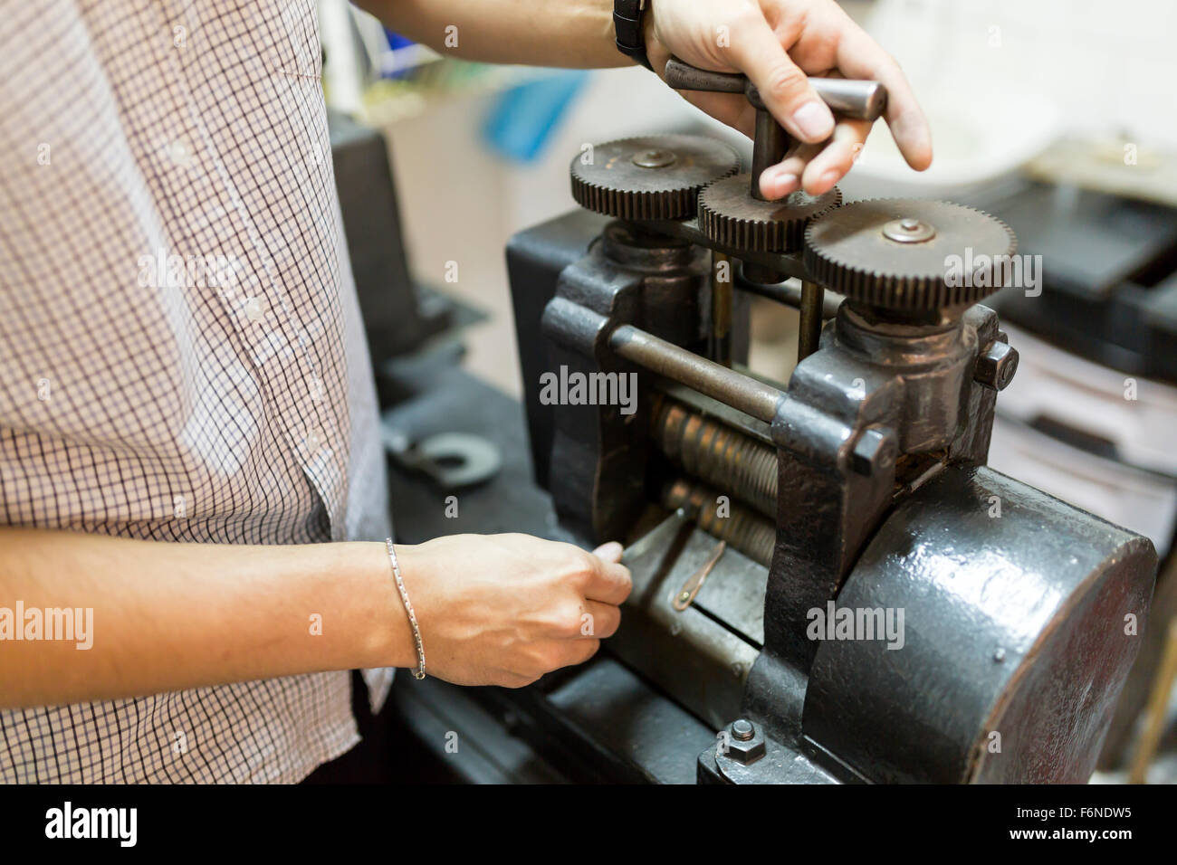 Goldsmith using machine to make metal thinner Stock Photo - Alamy