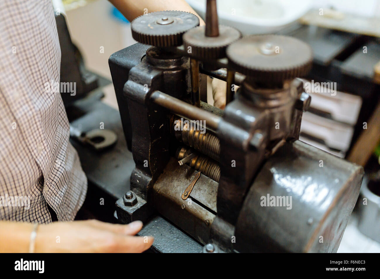 Goldsmith using machine to make metal thinner Stock Photo - Alamy