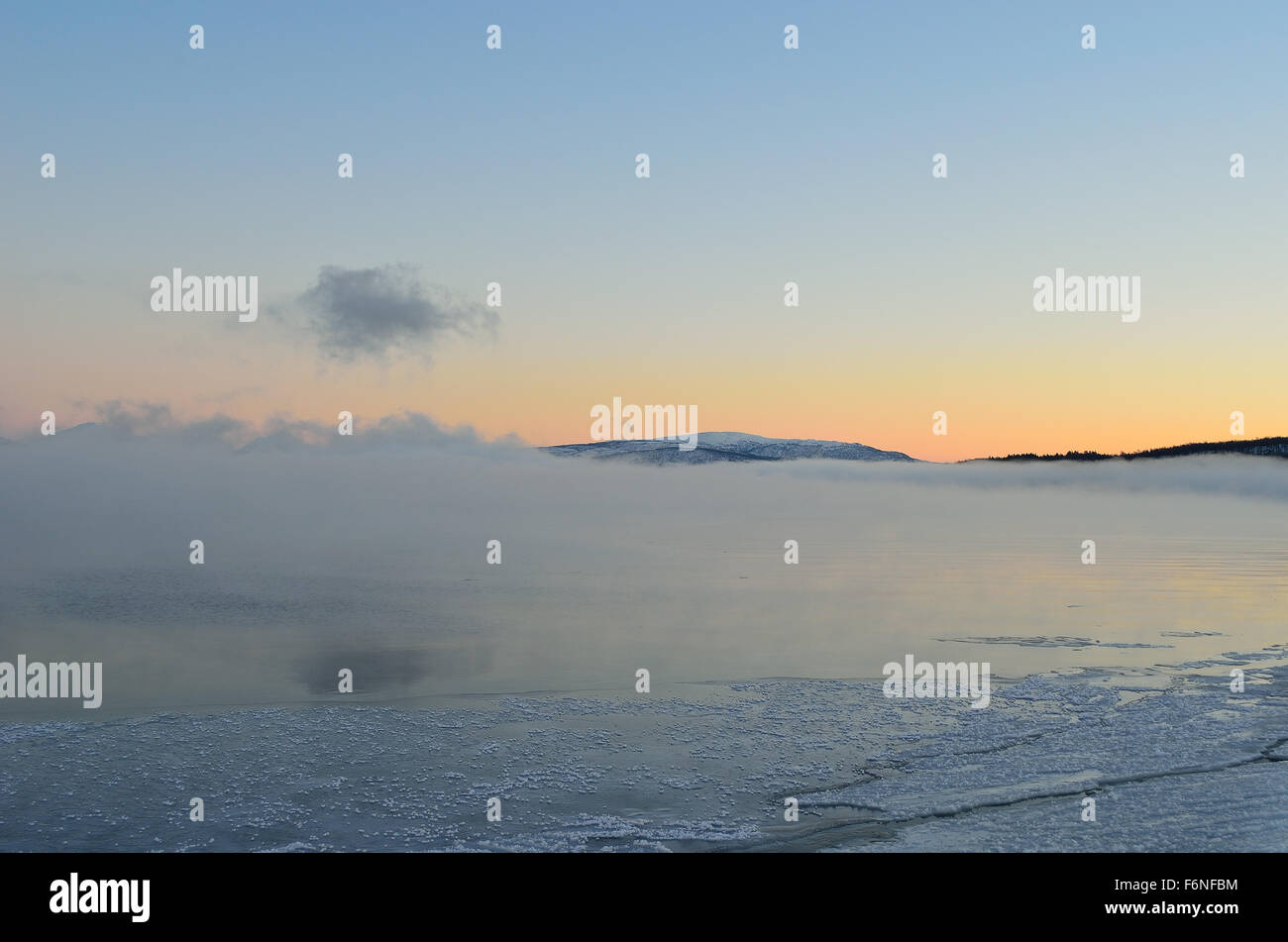 beautiful thick ice fog over cold fjord water with colorful sunset sky ...