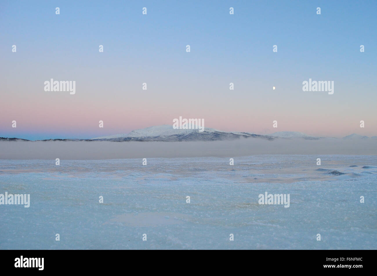 thick sea ice with cold ice frost fog and mist over water with pink ...