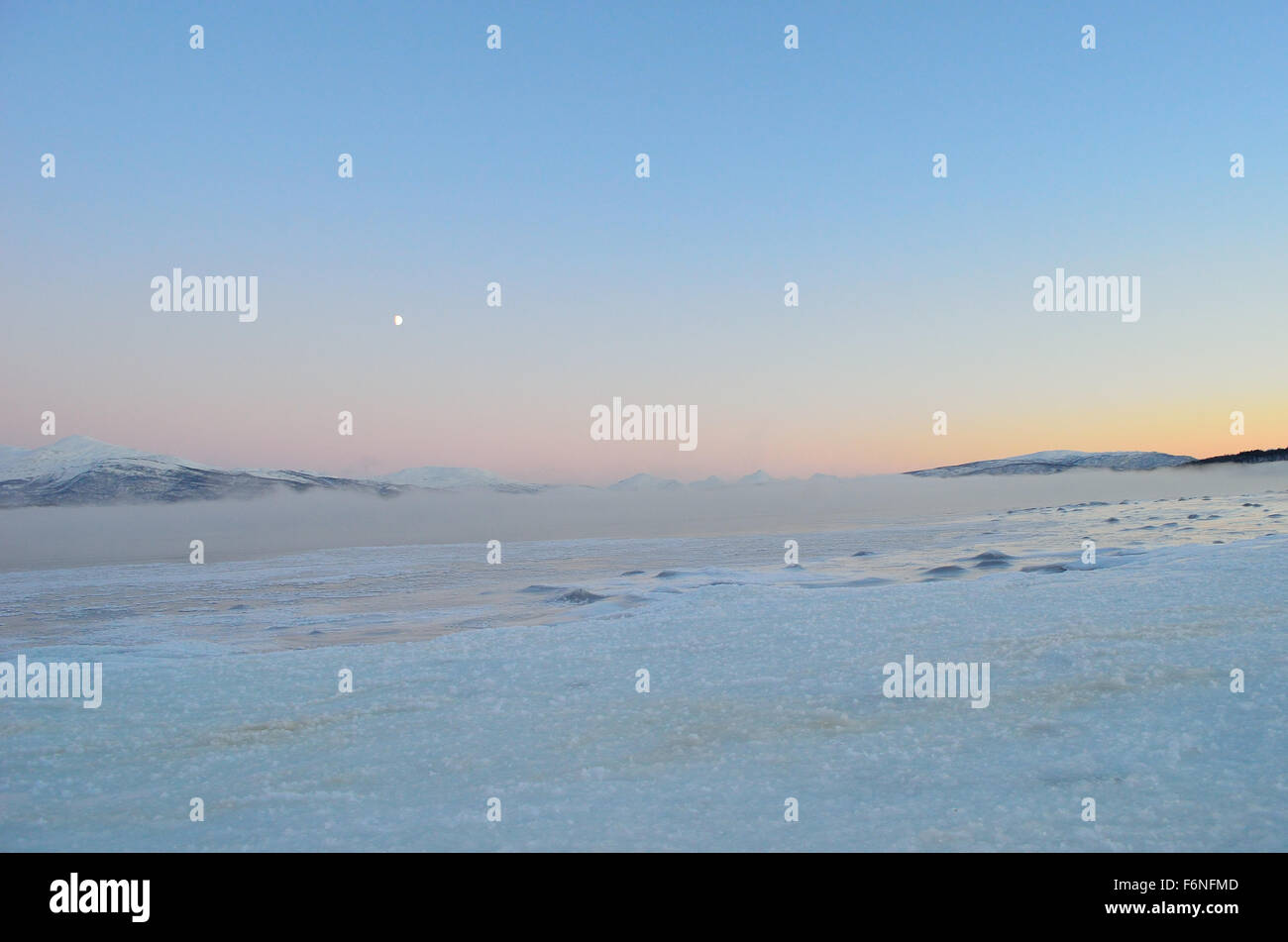thick sea ice with cold ice frost fog and mist over water with pink ...