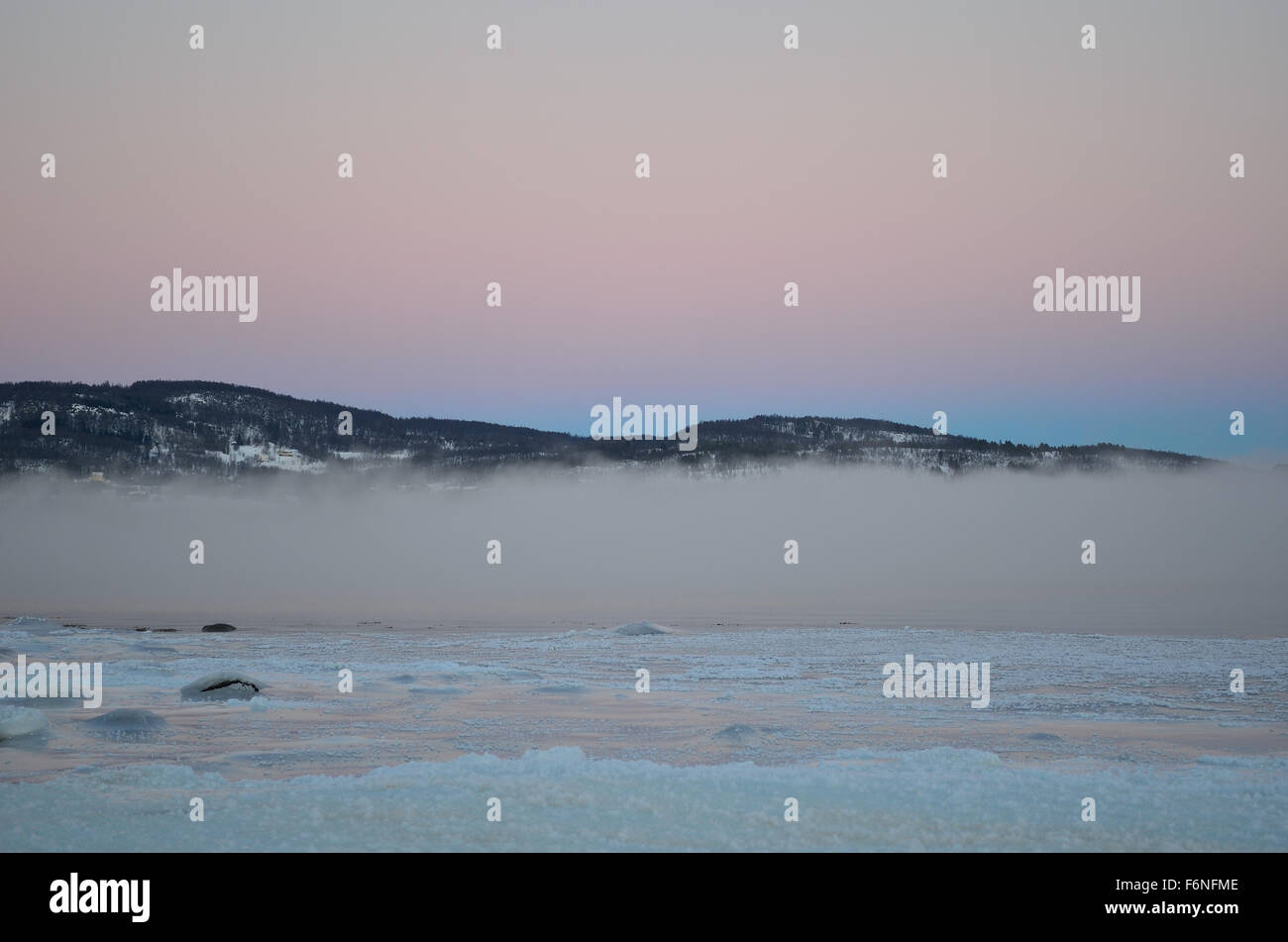 thick sea ice with cold ice frost fog and mist over water with pink ...