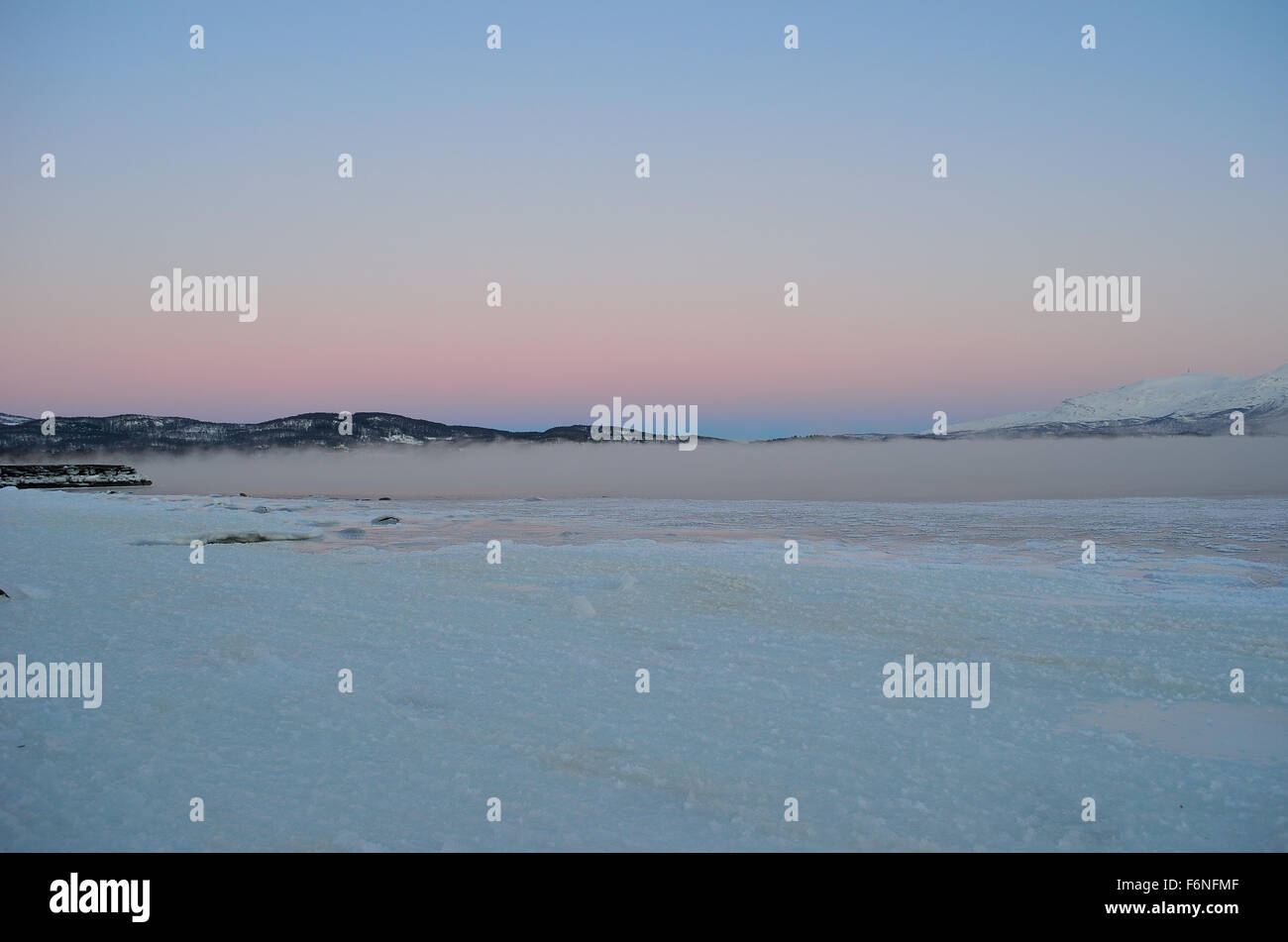 thick sea ice with cold ice frost fog and mist over water with pink ...