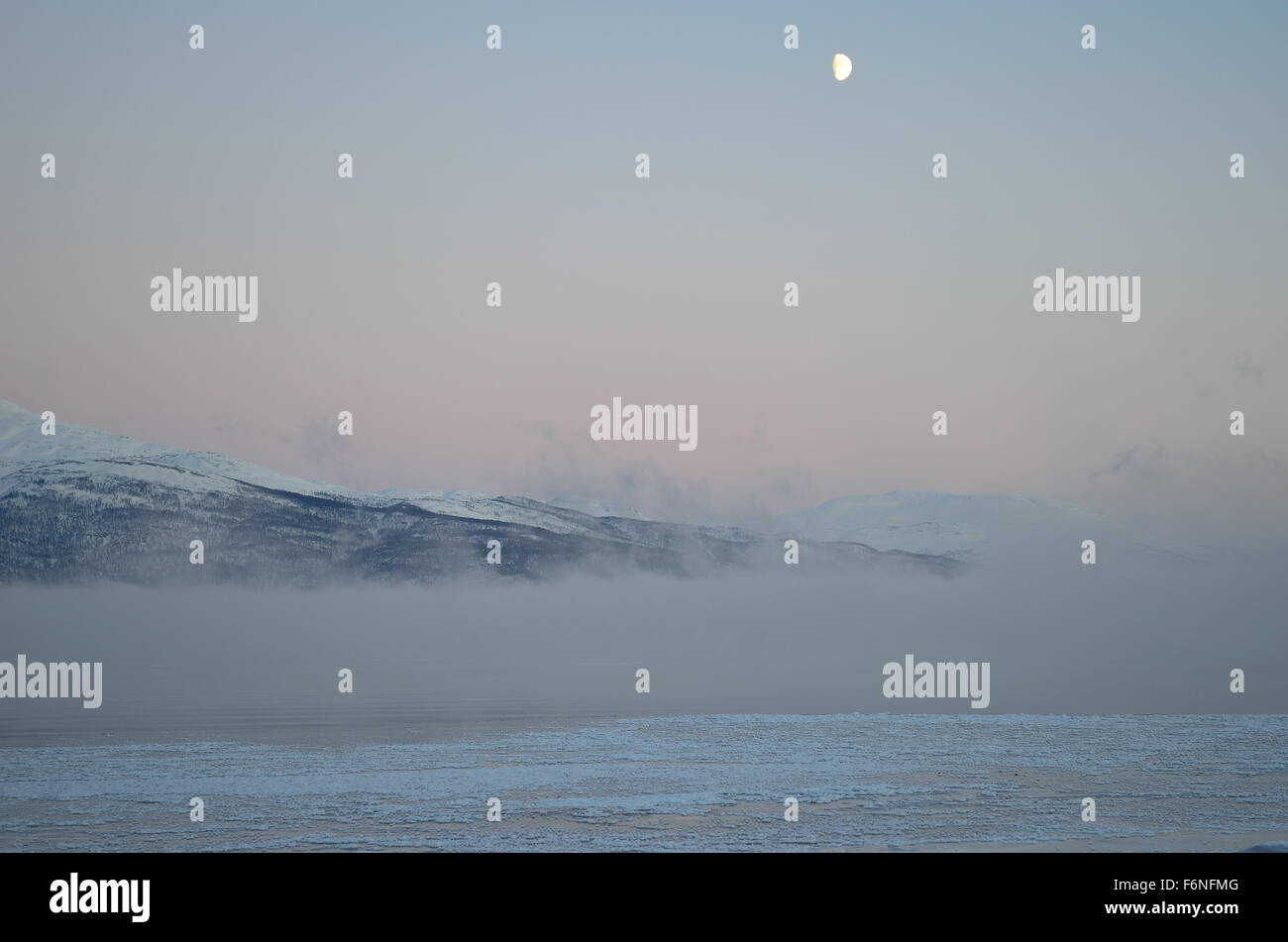 thick sea ice with cold ice frost fog and mist over water with pink ...
