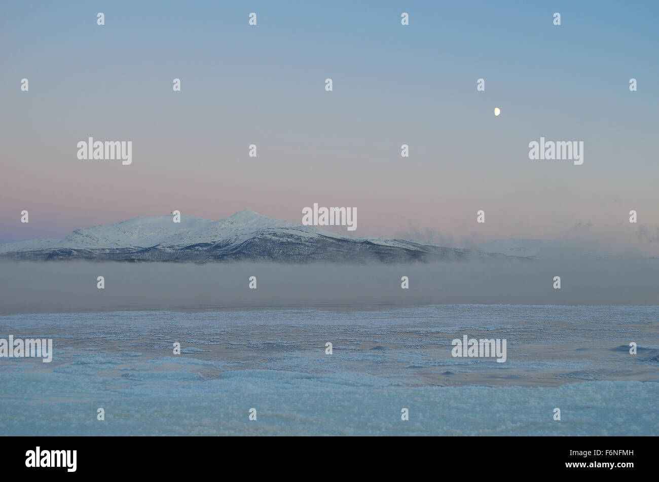 thick sea ice with cold ice frost fog and mist over water with pink ...