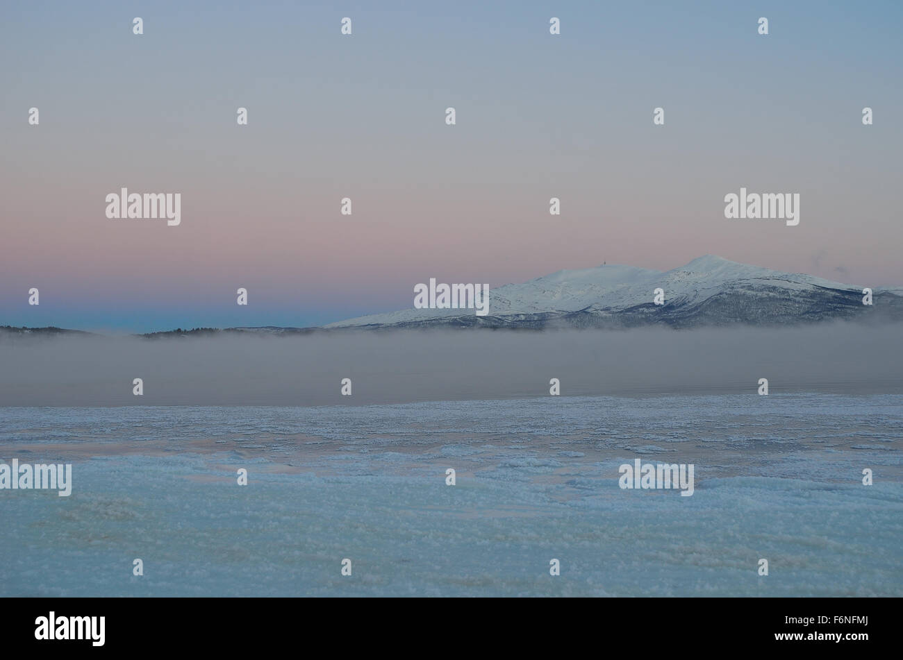 thick sea ice with cold ice frost fog and mist over water with pink ...